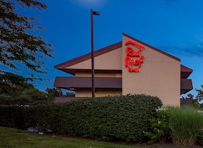 Um Red Roof Inn com design moderno, apresentando um telhado plano e uma placa vermelha chamativa.