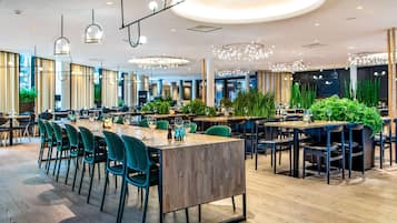 Um restaurante amplo, com pé-direito alto, iluminação moderna e diferentes opções de assentos.