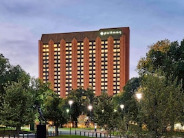 Um hotel com um letreiro chamativo da 'Pullman', rodeado por árvores e postes de iluminação.