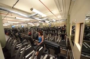Uma academia com esteiras, equipamentos de exercício e espelhos.