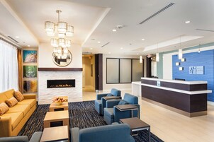 Um lobby moderno com lareira, área de estar e balcão de recepção.