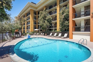 Piscina com espreguiçadeiras e um edifício com várias varandas.