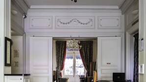 Um hall imponente com um candelabro, um tapete vermelho e uma mesa com um laptop.