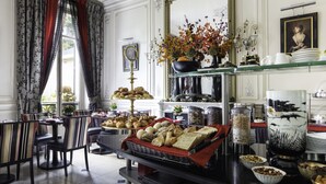 Espaço de refeições com mesa de buffet, cadeiras e um candelabro.