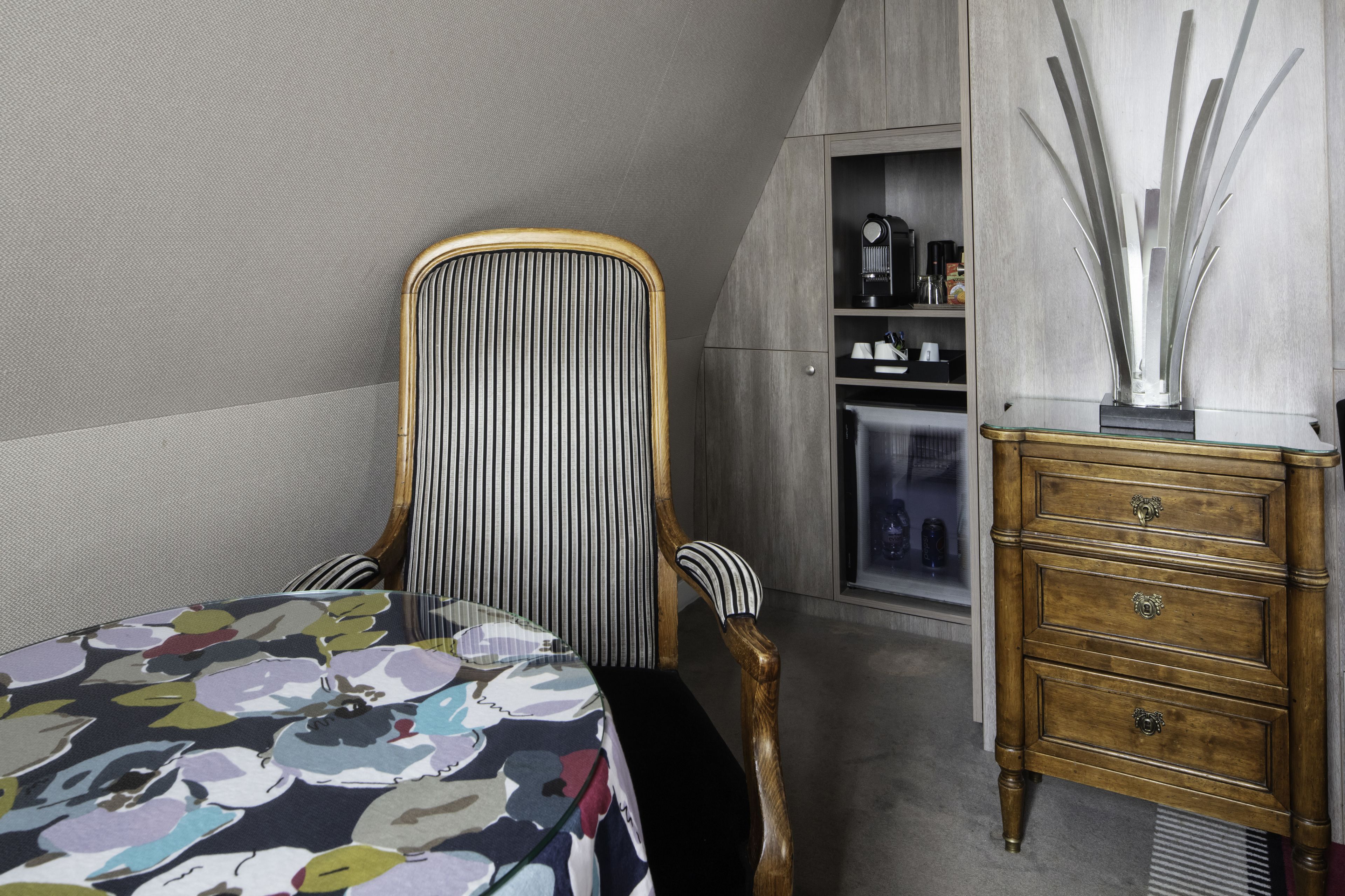Um quarto com uma cama, uma cadeira, uma cômoda e uma estante com diversos objetos.