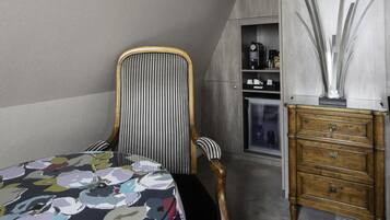 Um quarto com uma cama, uma cadeira, uma cômoda e uma estante com diversos objetos.