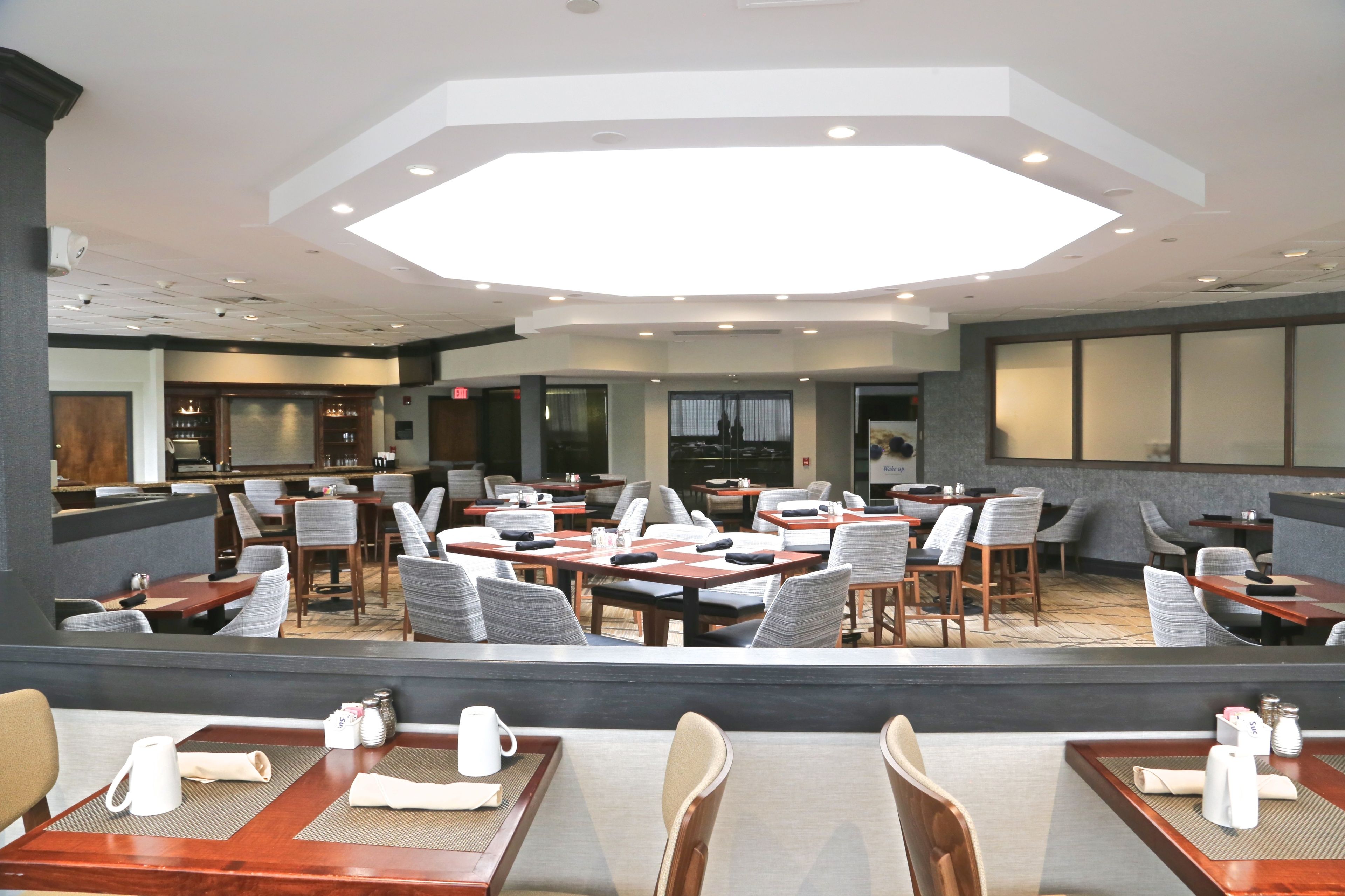 Restaurante moderno com várias áreas de refeição, incluindo um bar e cabines privativas.