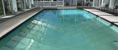 Piscina límpida com teto de vidro, rodeada por um revestimento de tijolos, e indicador de profundidade de 90 centímetros.