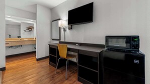 Quarto de hotel com escrivaninha, cadeira, televisão de ecrã plano e micro-ondas.