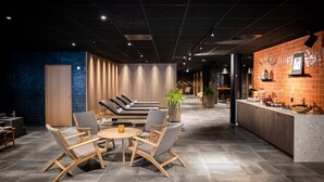 Uma área de lounge moderna com bar, assentos e um vaso de planta.