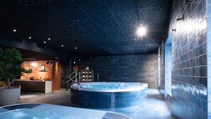 Área de spa com duas banheiras de hidromassagem, um balcão de recepção e uma parede com efeito de teto estrelado.