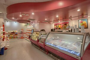 Uma gelataria com interior rosa, vitrines refrigeradas e diversas opções de sabores de gelato.