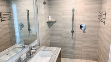 Uma casa de banho moderna com chuveiro em cabine de vidro, lavatório de mármore e porta-toalhas.
