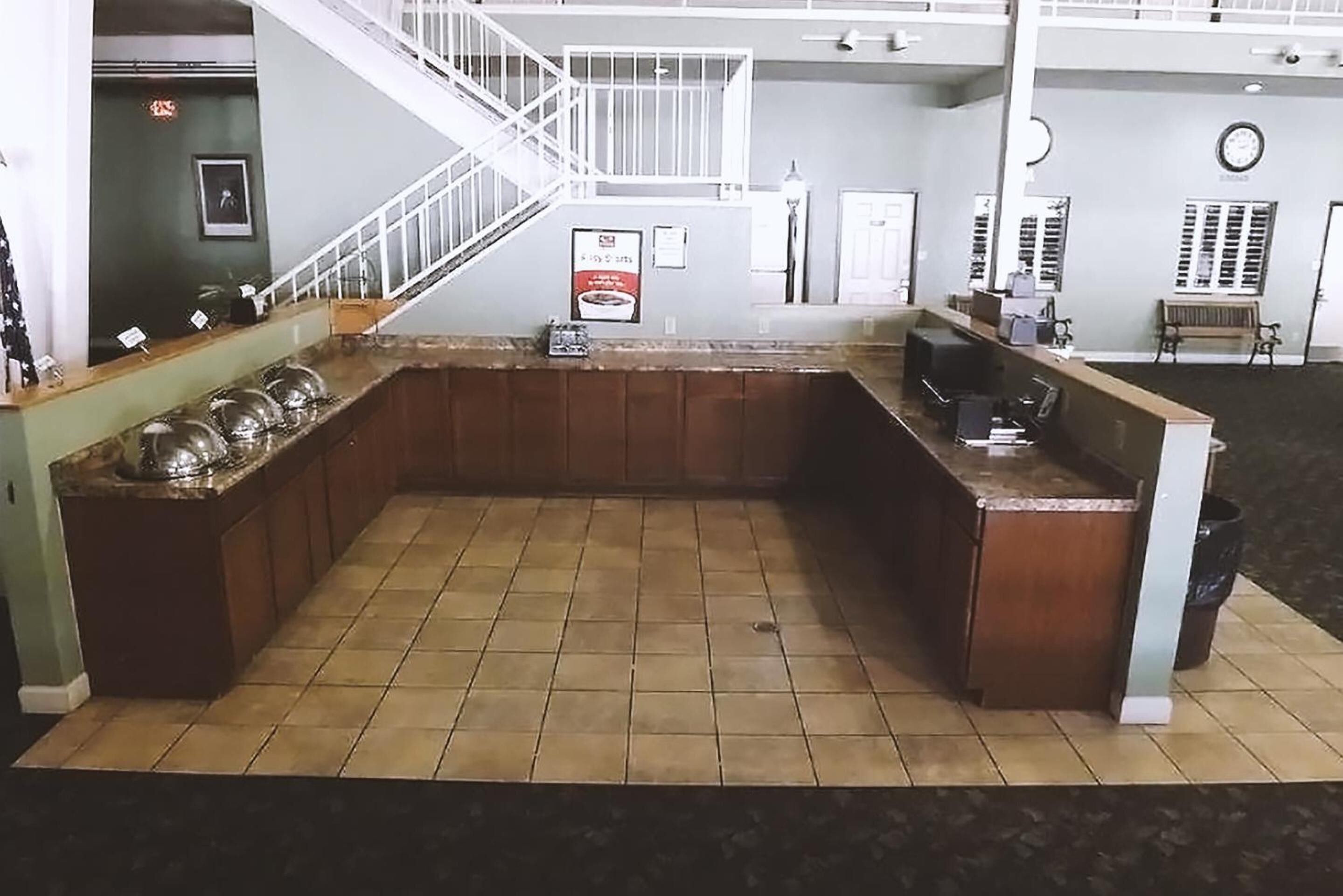 Uma cozinha com ilha central, escada e bancada com um computador.