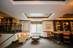 Uma área de bar com disposição de assentos, uma escadaria e vista para o exterior.