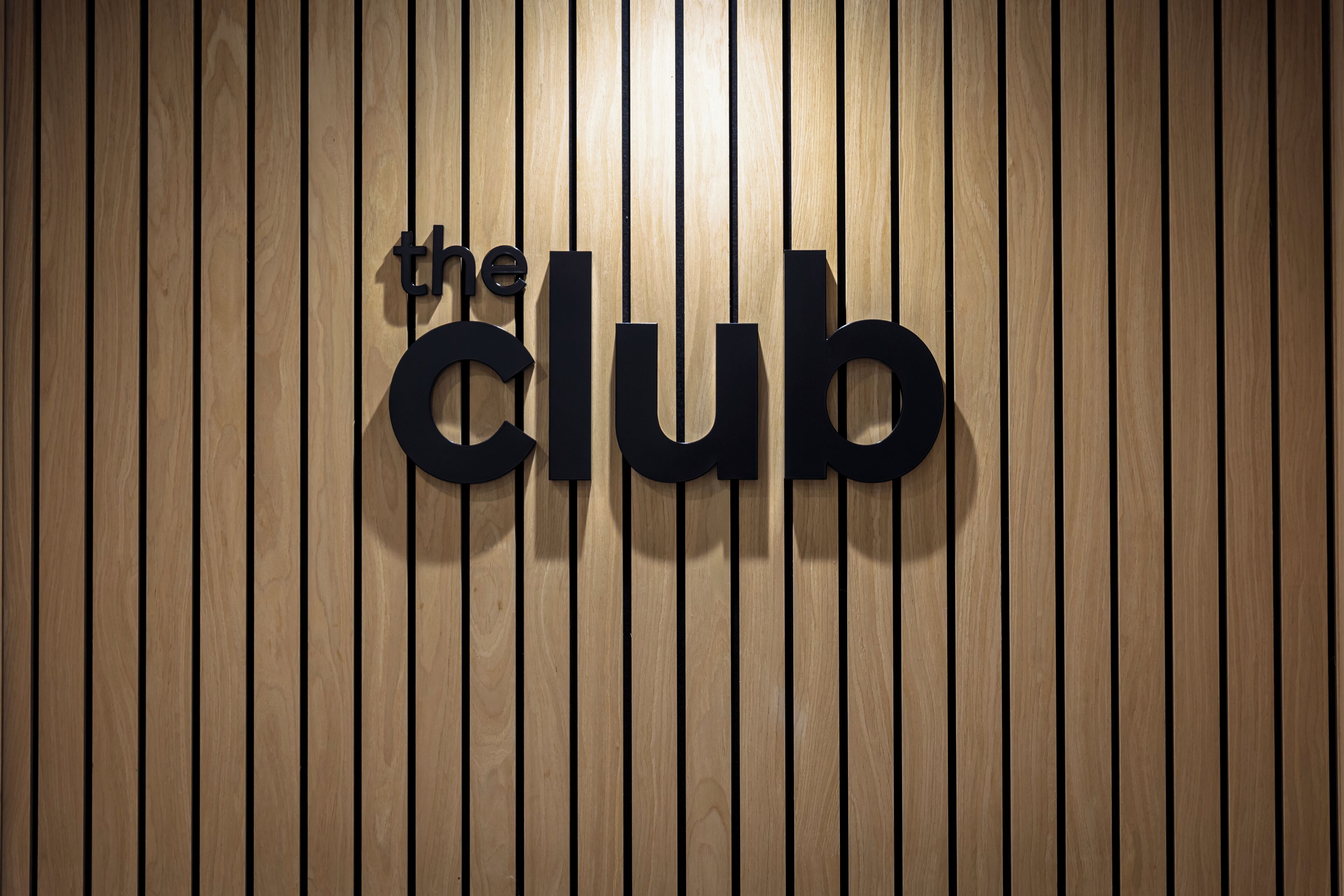 Pared de madeira com a inscrição "the club" em letras pretas.