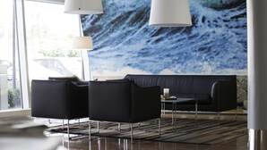Um lobby moderno com um grande mural abstrato, assentos de couro preto e luminárias pendentes.