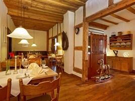Uma área de refeições com mesas e cadeiras de madeira, luminárias pendentes e decoração rústica.