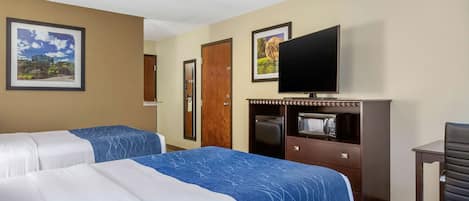 Quarto de hotel com duas camas, televisão, escrivaninha e uma cadeira.