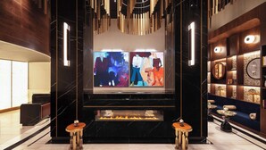 Um hall moderno com lareira de mármore preto, detalhes em madeira e uma exposição de arte digital.