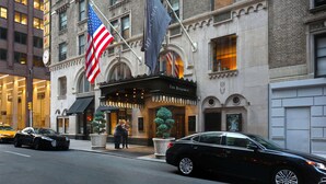 Um hotel com fachada clássica, exibindo uma bandeira americana e um letreiro com a inscrição 'The Benjamin'.