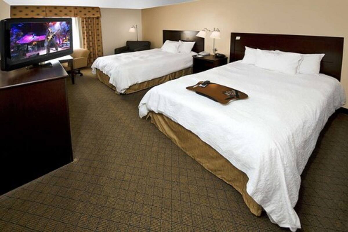 Quarto de hotel com duas camas, televisão, escrivaninha e cadeira.
