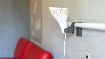 Suporte de bola de badminton branco fixado na parede, com uma cadeira vermelha visível ao fundo.