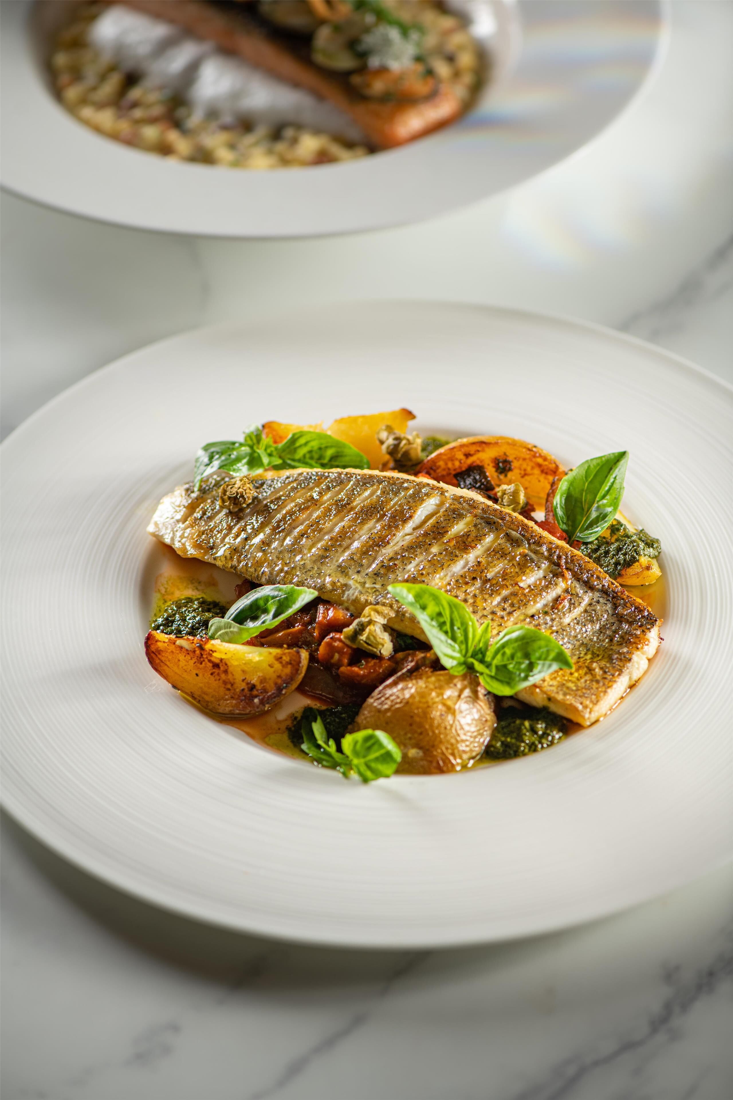 Um prato de comida com filé de peixe, vegetais e ervas.