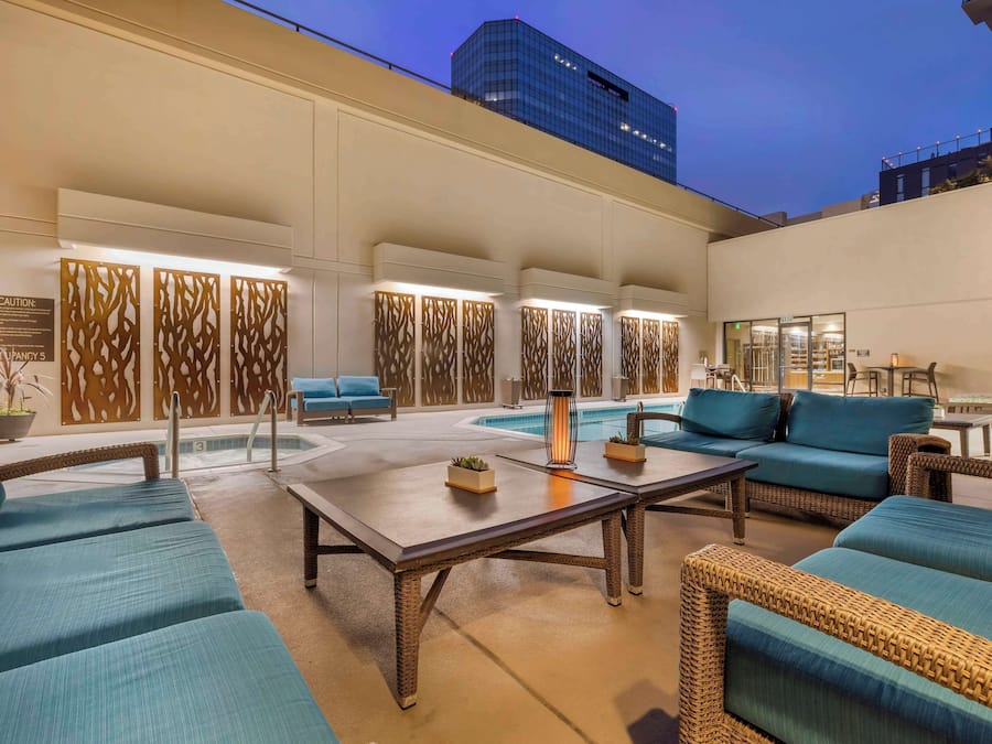 Uma área de piscina com móveis de vime, piscina e um edifício ao fundo.