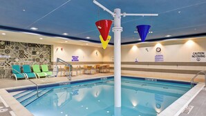 Piscina interior com água cristalina, zonas de profundidade demarcadas e placas de segurança.
