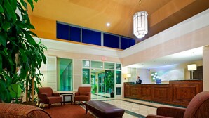 Um saguão de hotel com balcão de recepção, área de estar e uma grande janela.