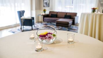 Um quarto bem iluminado com uma mesa redonda, uma peça central em forma de cúpula de vidro com flores e velas.