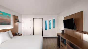 Quarto de hotel com uma cama grande, uma escrivaninha com televisão de tela plana, um armário de madeira e obras de arte nas paredes.