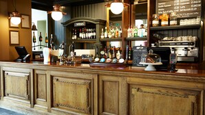 Um balcão de bar com design de madeira, uma estante de vinhos ao fundo e uma máquina de café à direita.