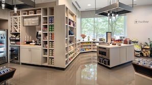 Loja limpa e bem organizada, com prateleiras repletas de diversos produtos, uma área refrigerada e um balcão de atendimento.