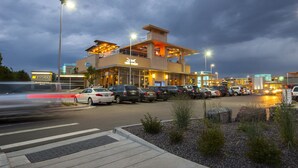 Hotel com vários andares e design moderno, com um terraço no telhado e área de estacionamento bem iluminada.