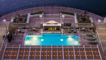 Uma área de piscina no terraço com espreguiçadeiras e um espaço para relaxar.