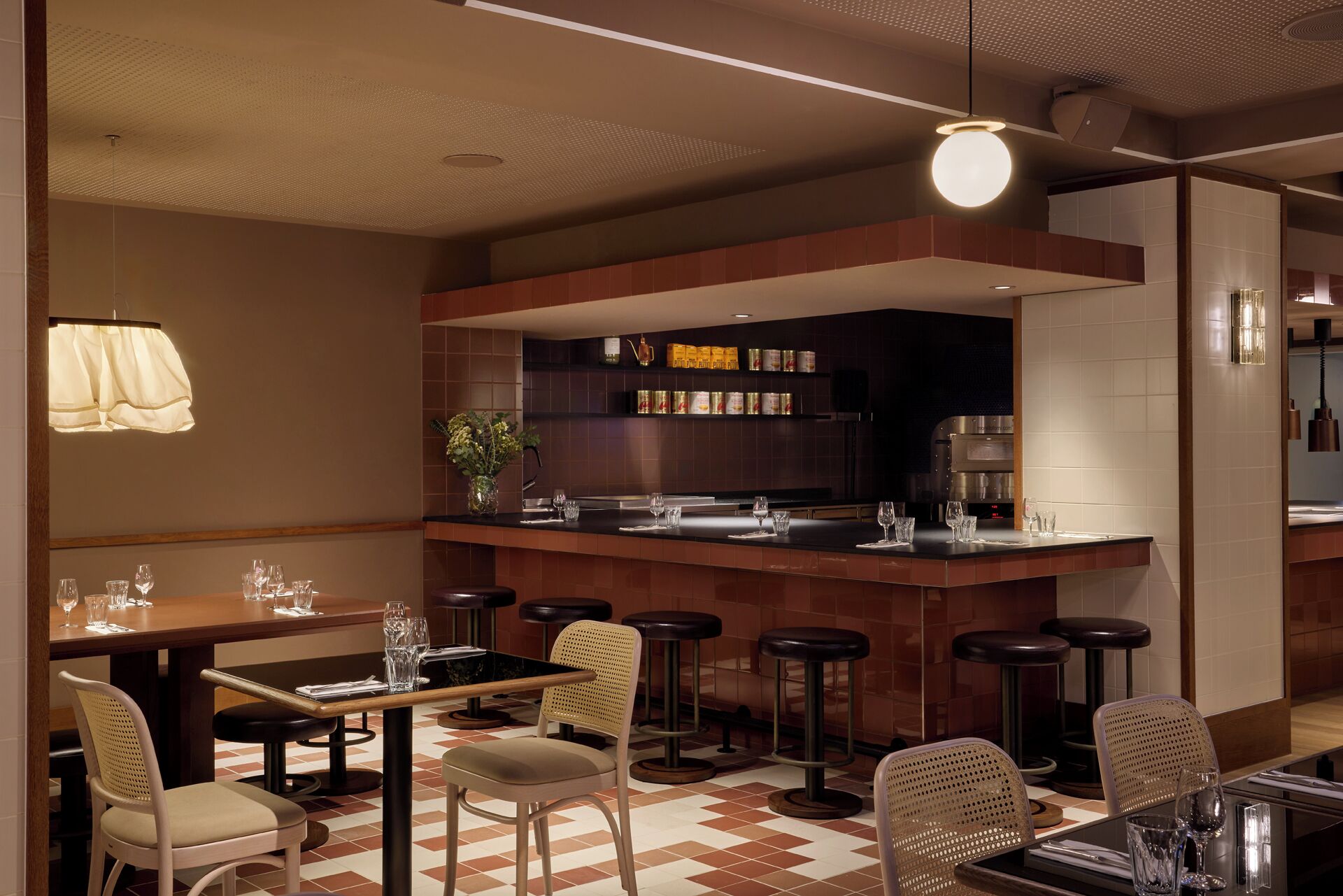 Restaurante com área de bar, diversas opções de assentos e cozinha ao fundo.