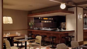 Restaurante com área de bar, diversas opções de assentos e cozinha ao fundo.
