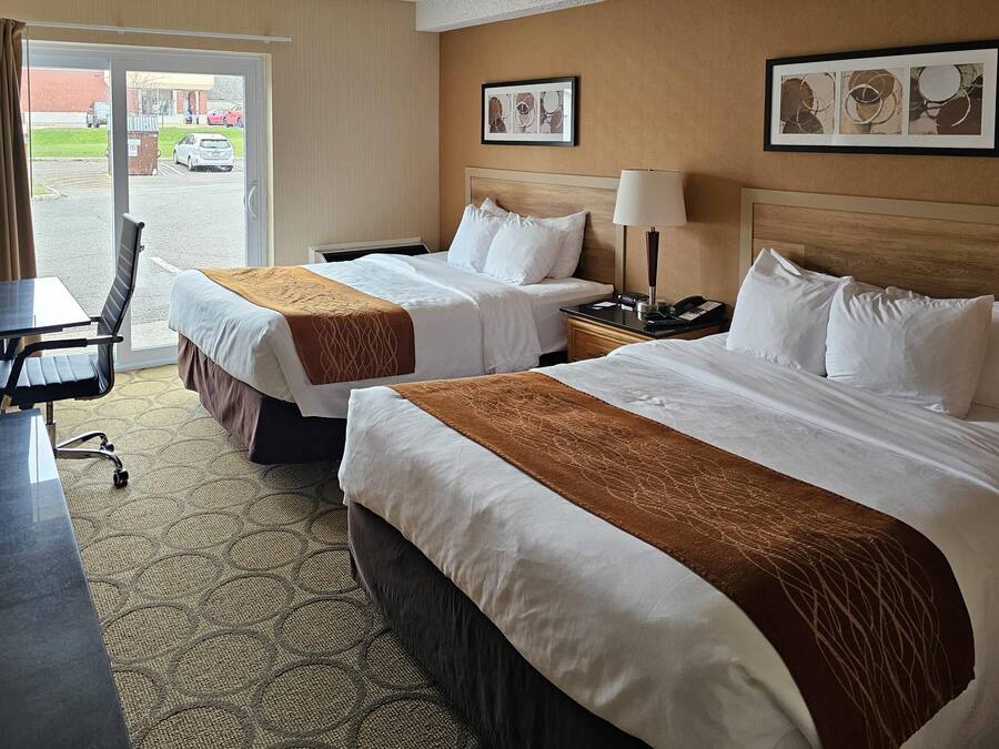 Quarto de hotel com duas camas, uma escrivaninha e uma cadeira.