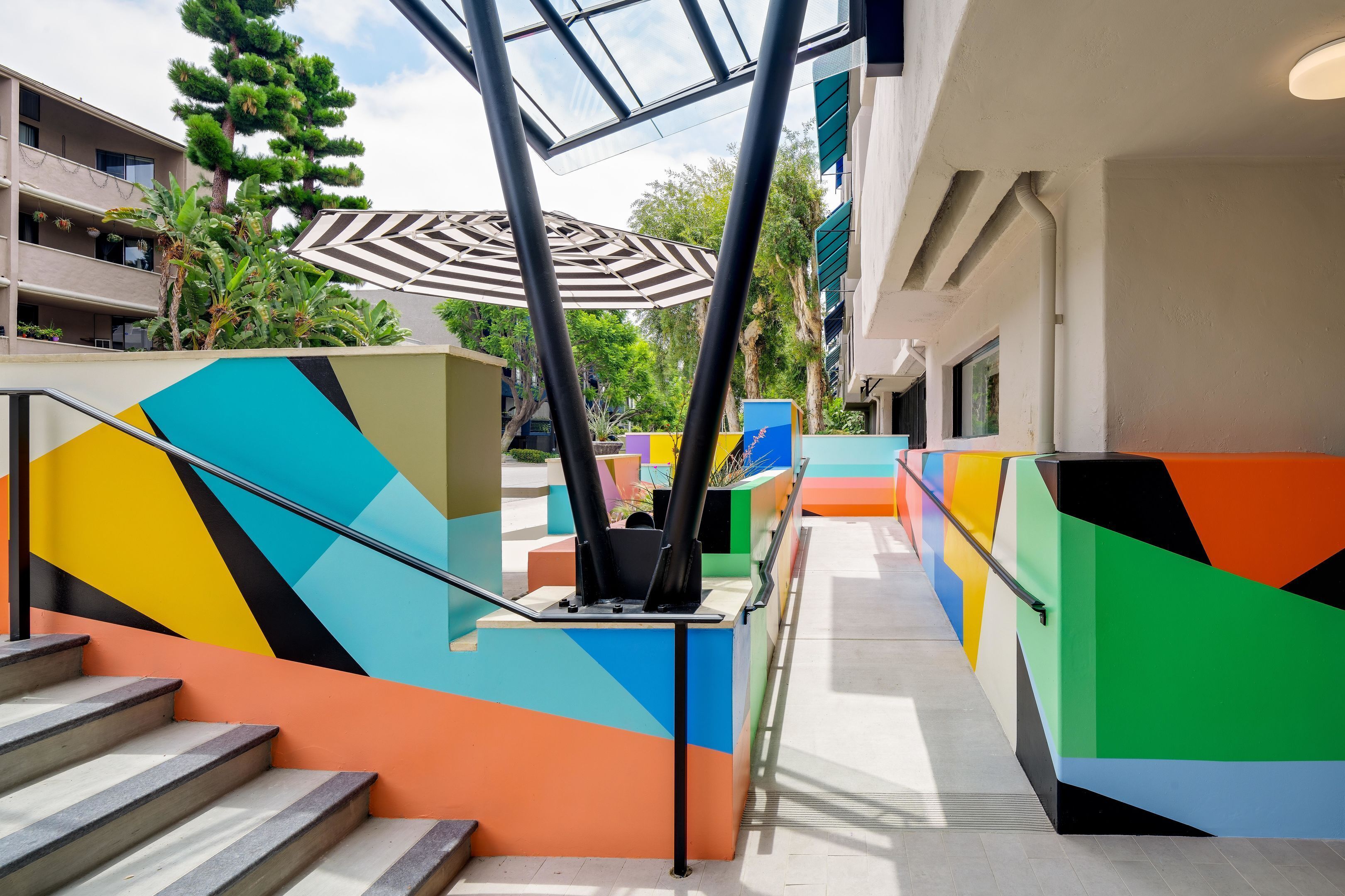 Um edifício moderno com padrões geométricos coloridos nas paredes e uma escada com grades de metal.