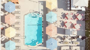Vista aérea de uma área de piscina com vários guarda-sóis, espreguiçadeiras e uma piscina.