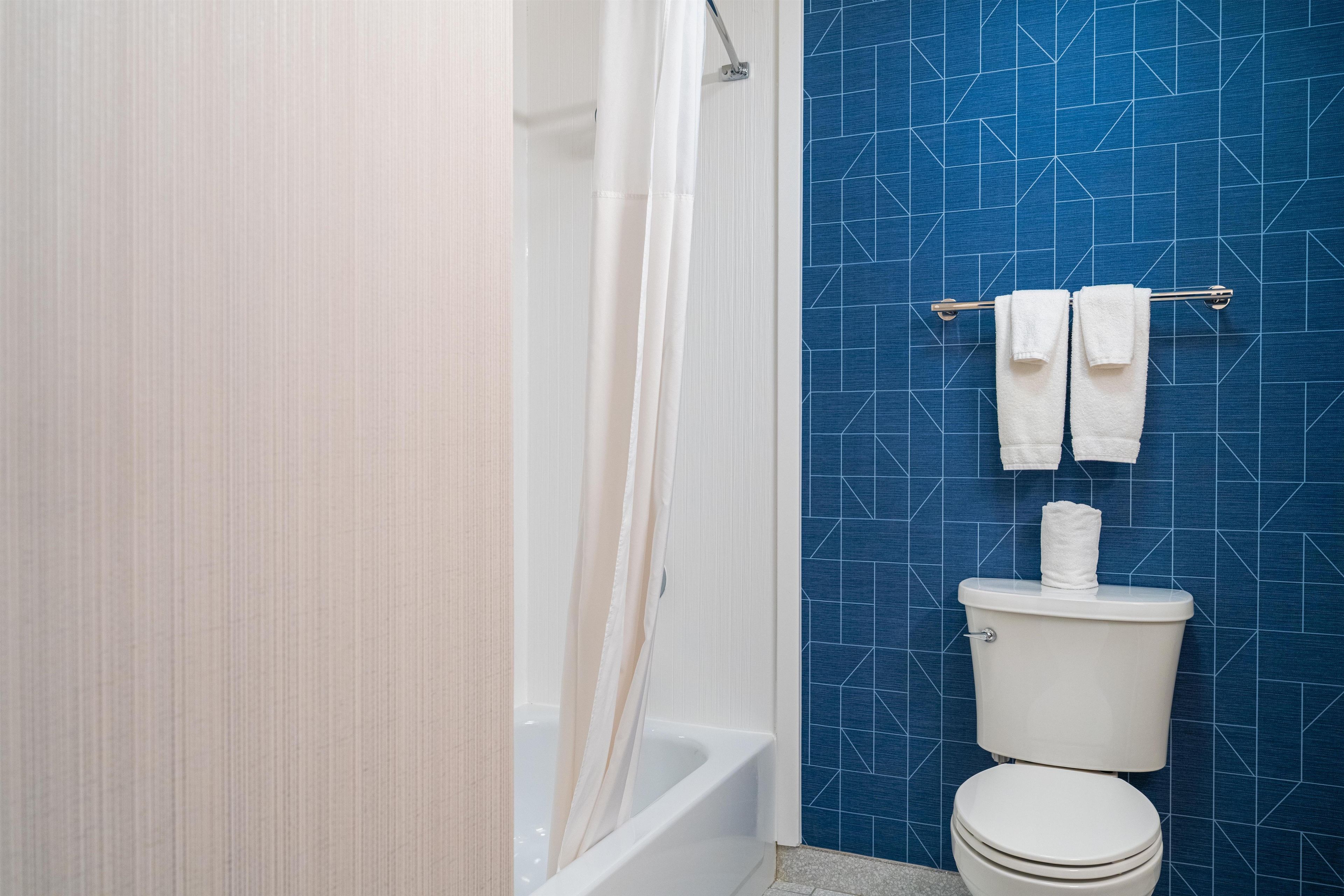 Um banheiro com banheira, vaso sanitário e porta-toalhas com duas toalhas.
