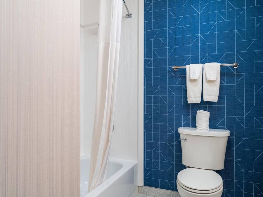 Um banheiro com banheira, vaso sanitário e porta-toalhas com duas toalhas.
