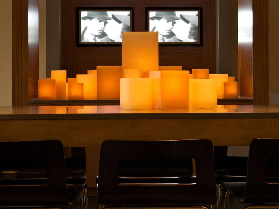 Uma sala de conferências com uma longa mesa, quatro fotografias emolduradas na parede e várias velas acesas.