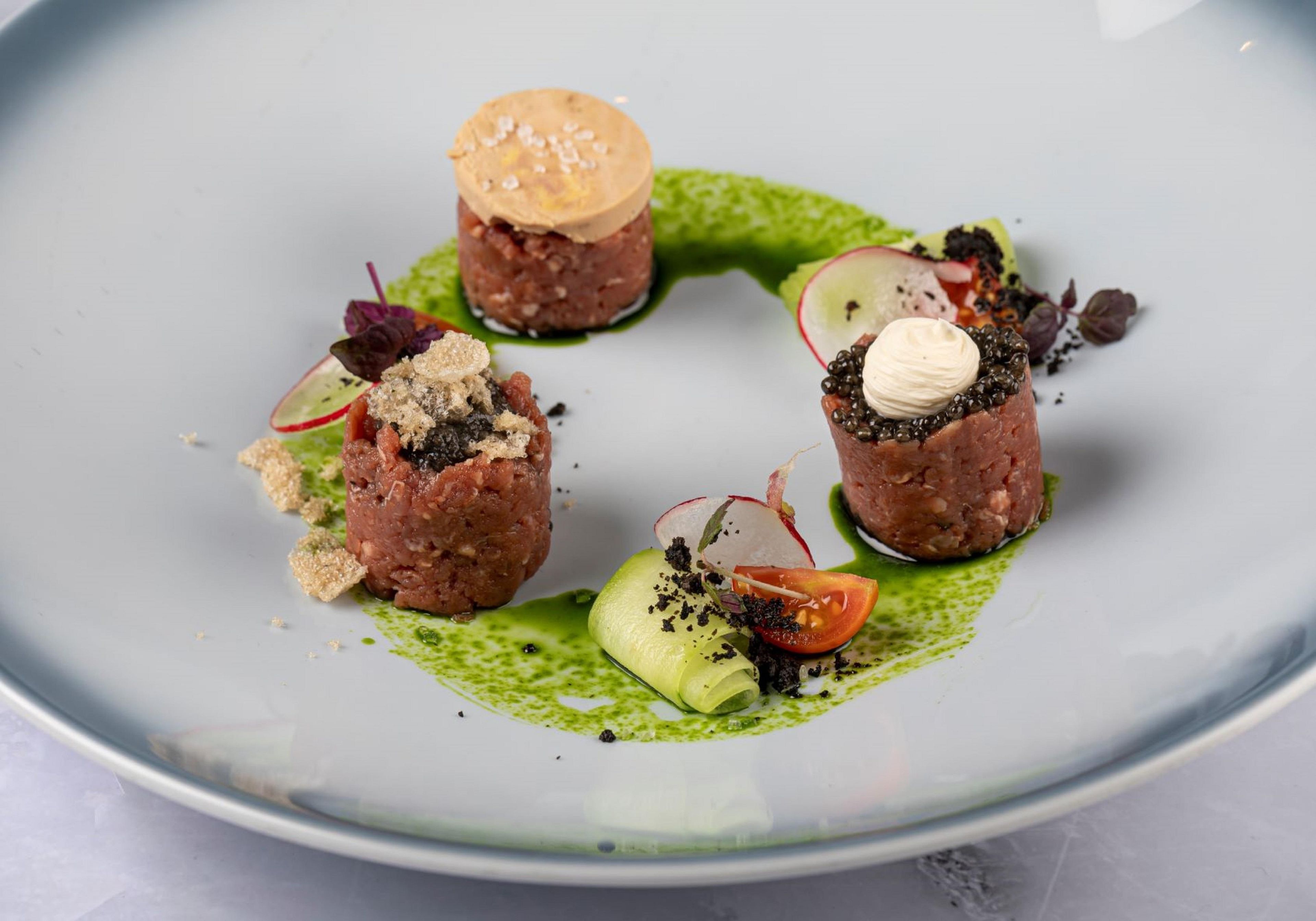 Um prato com três refeições à base de carne, decorado com ervas e vegetais.