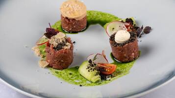 Um prato com três refeições à base de carne, decorado com ervas e vegetais.