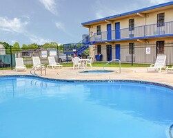 Uma área de piscina com espreguiçadeiras e um edifício com fachada azul e varanda.