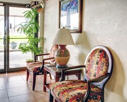 Um saguão com uma cadeira de madeira, uma mesa com abajur e um vaso de planta.