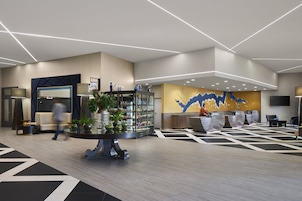 Um lobby moderno com balcão de recepção, área de estar e plantas decorativas.